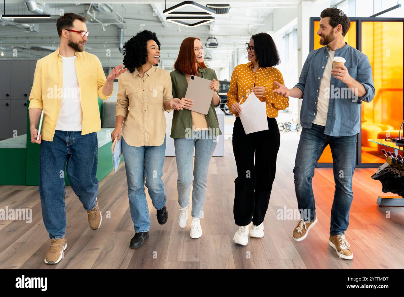 Group of five happy business people walking and talking together in a ...