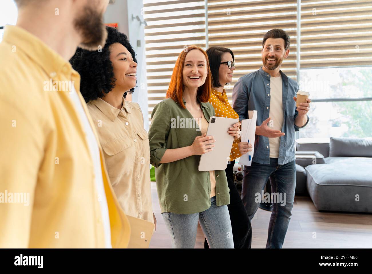 Diverse, happy business team walks through a modern office, talking and ...