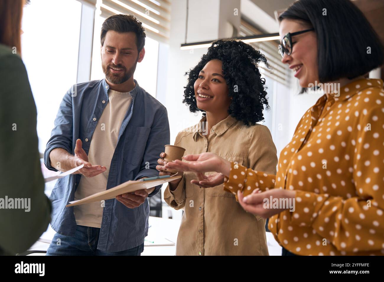 Group of business people are standing in an office setting, engaged in ...