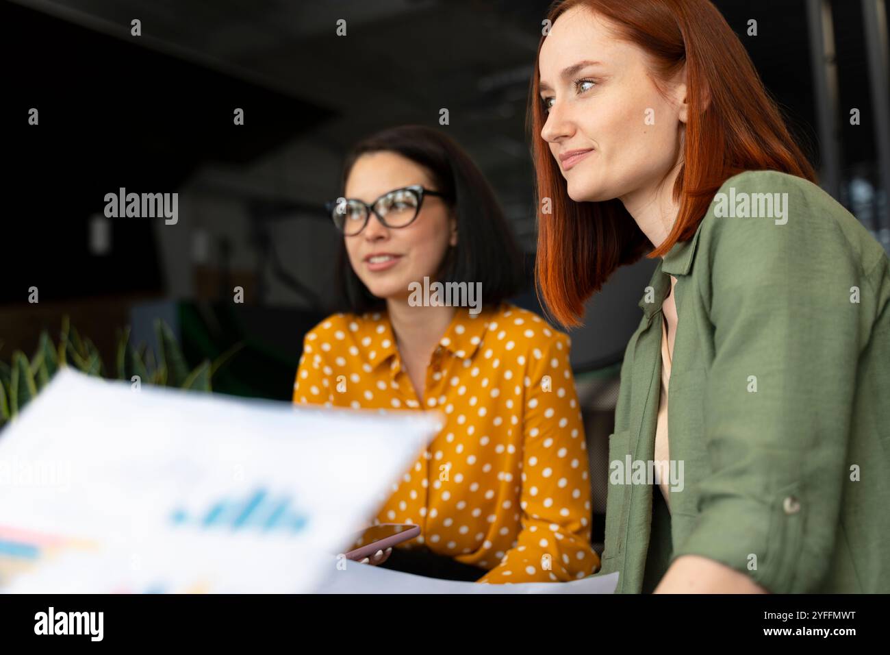 Two businesswomen deeply engaged in a presentation, showcasing ...