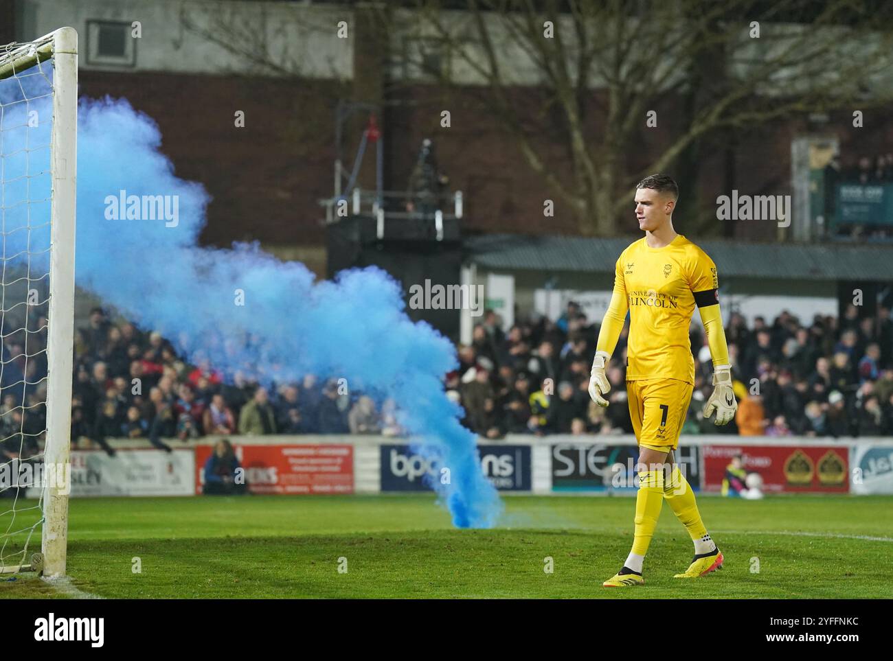 Lincoln City's George Wickens waits as a smoke flare is remove from the ...