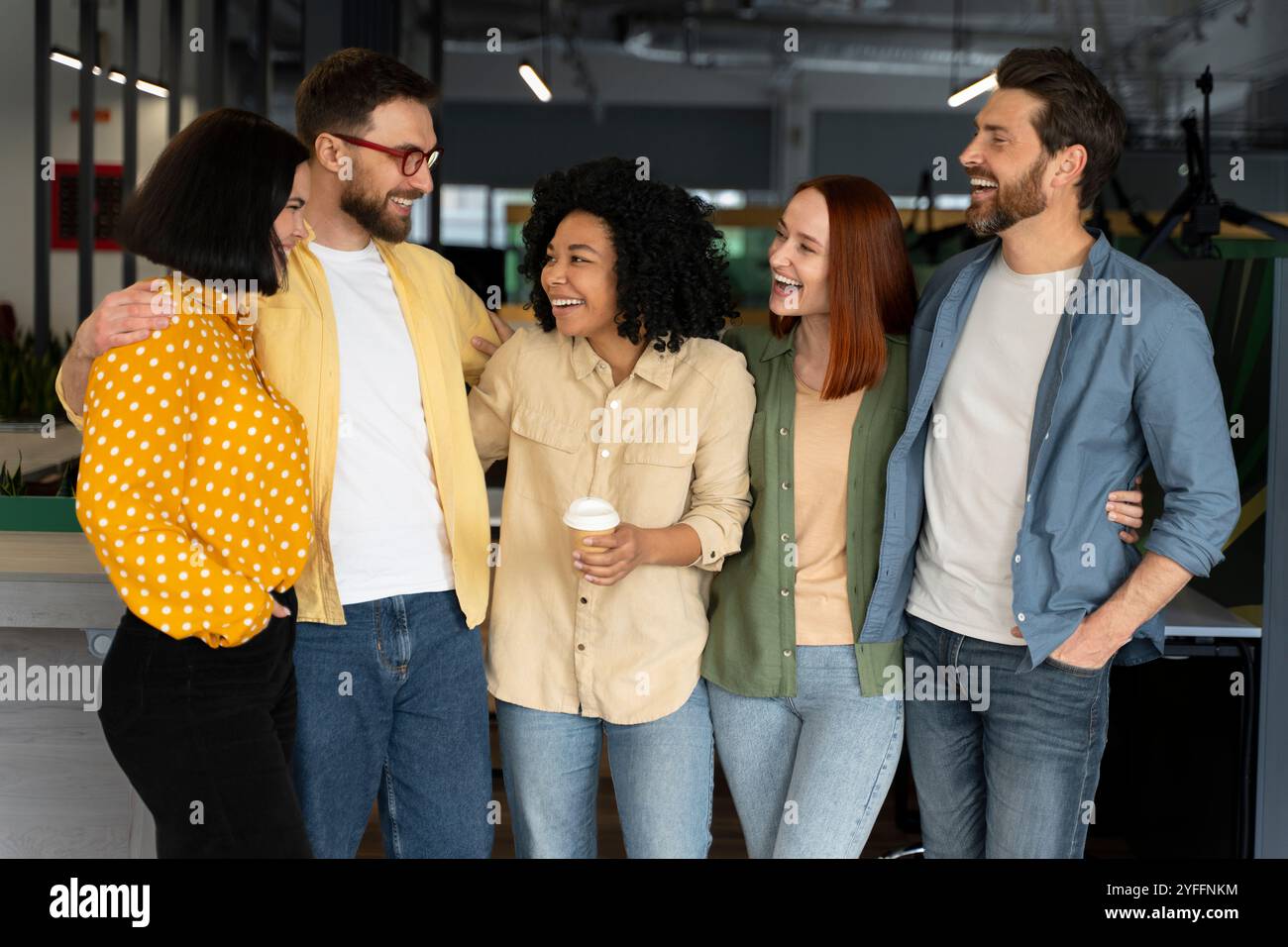 Group of five colleagues are standing together, their arms around each ...