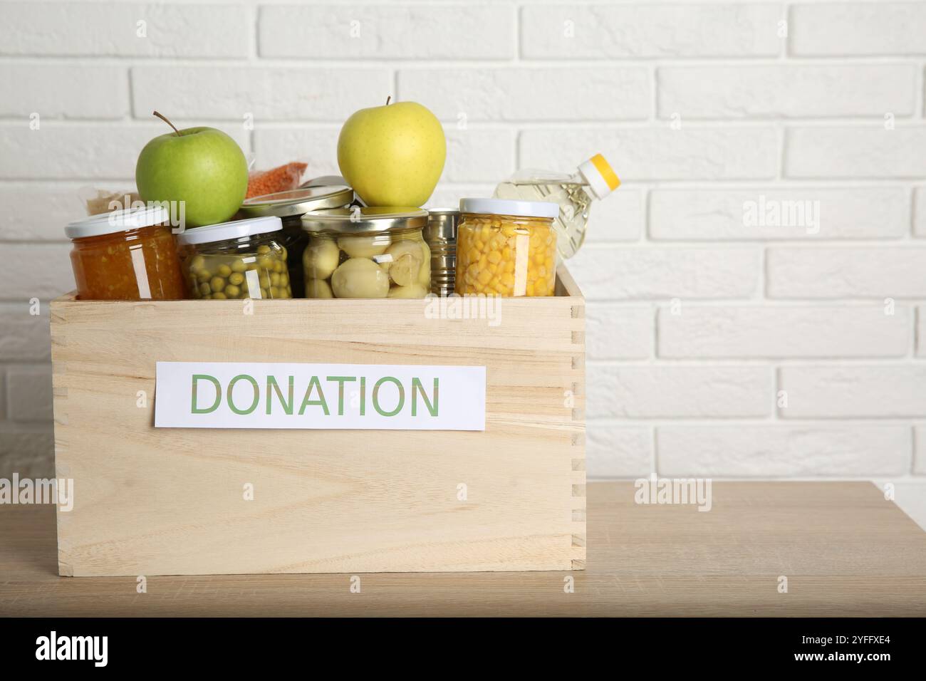 Different food products for donation in wooden crate on table near ...