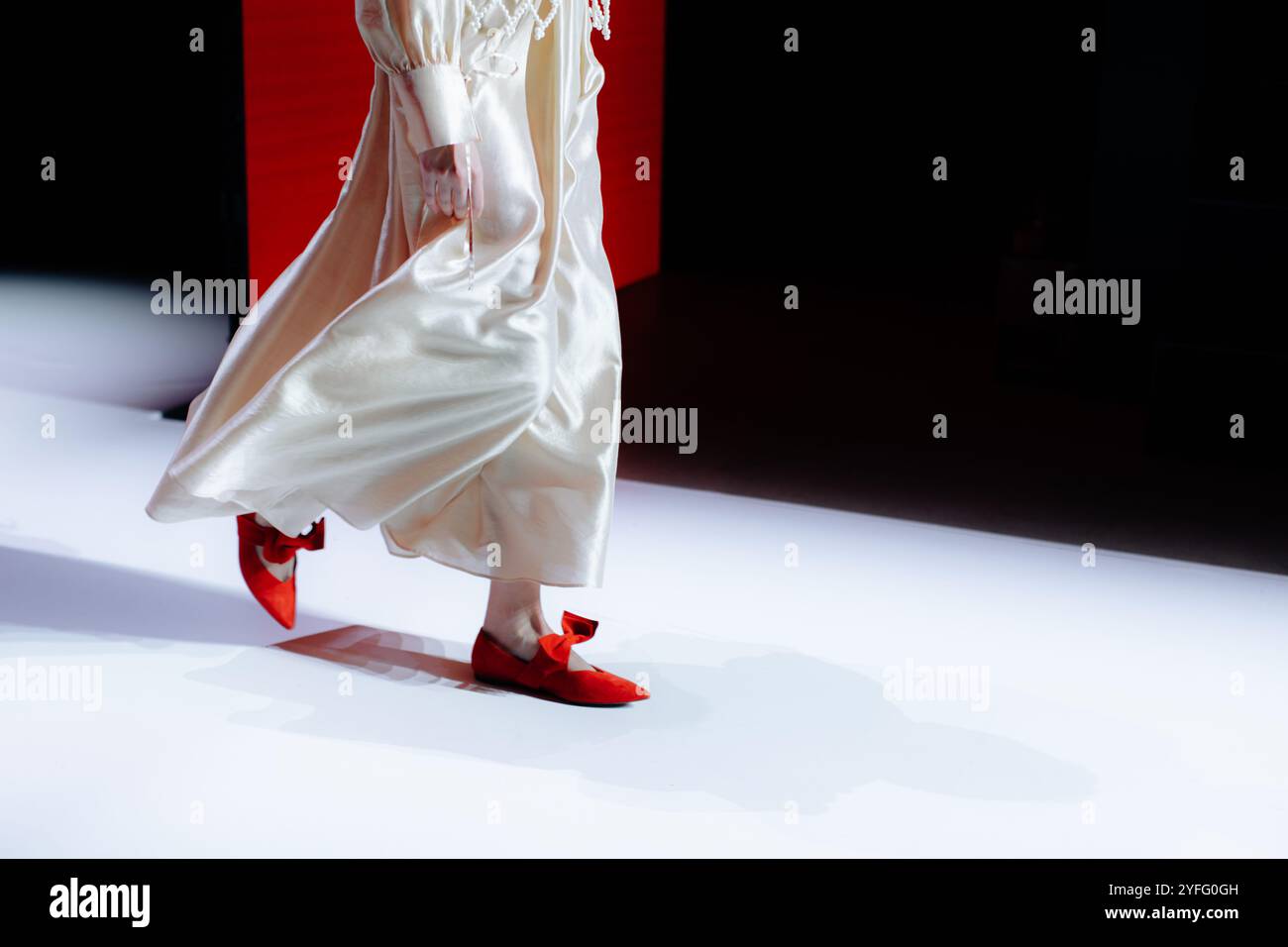 White silk long dress and bright red shoes with bows. Fashion model ...