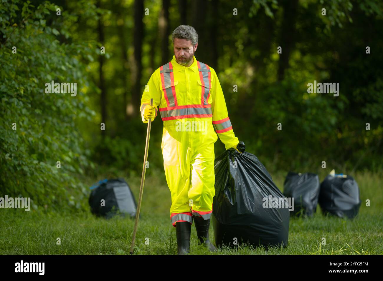 Volunteer in rubber gloves with trash bag clean up garbage on forest ...
