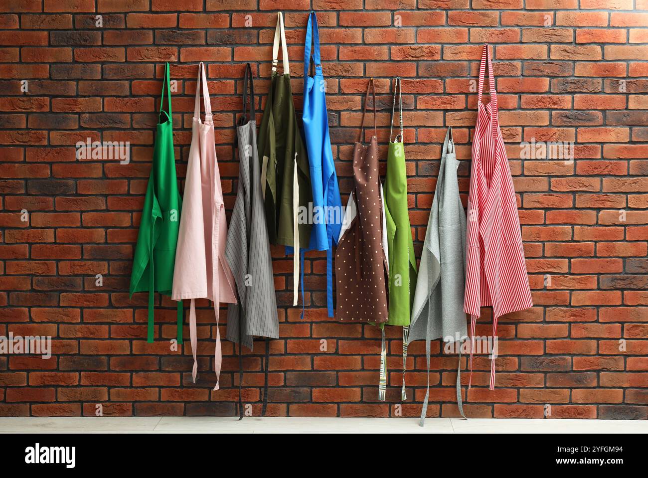 Many chef's aprons hanging on brick wall Stock Photo - Alamy