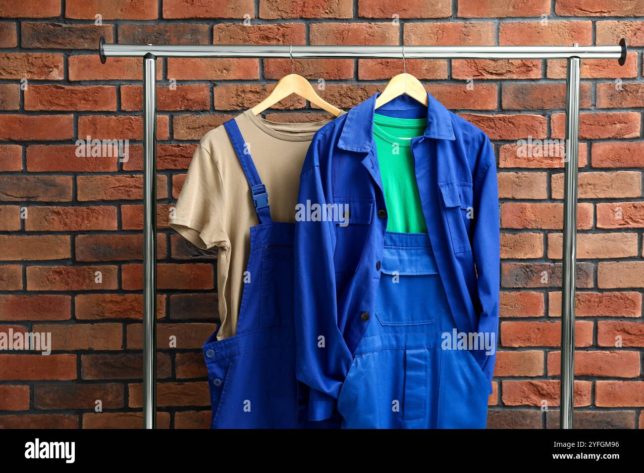 Workers' uniforms on clothing rack near brick wall Stock Photo - Alamy