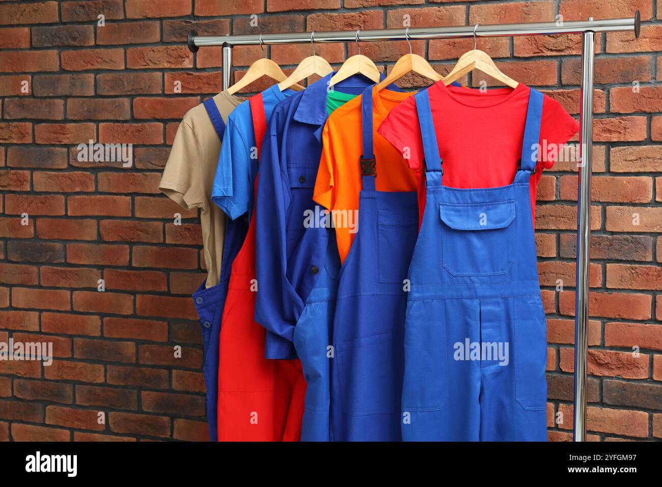 Different workers' uniforms on clothing rack near brick wall Stock ...