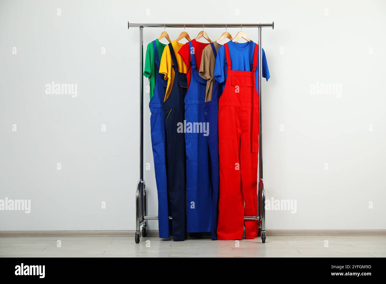 Workers' uniforms on clothing rack near grey wall indoors Stock Photo ...