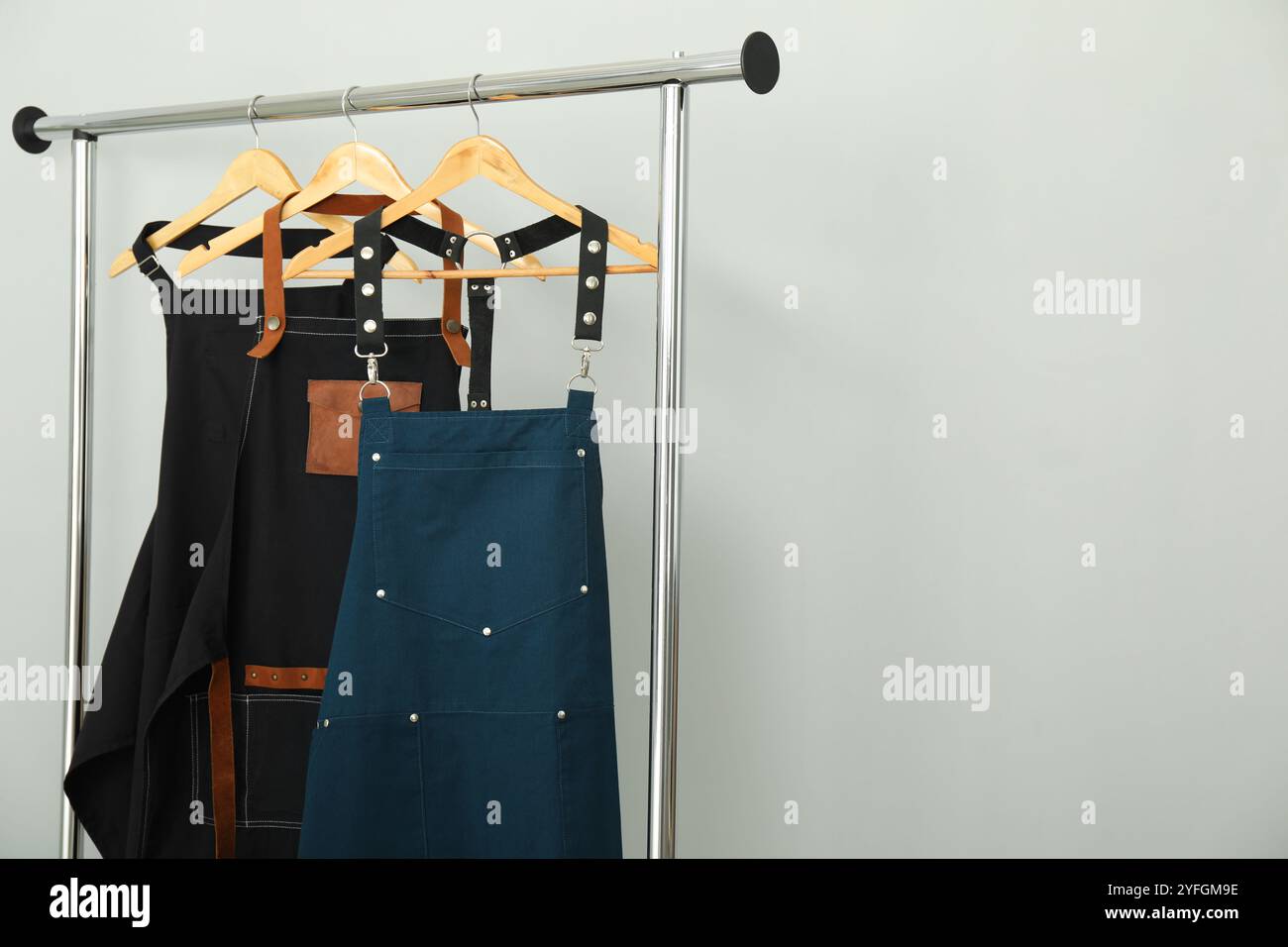 Aprons on clothing rack near light grey wall, space for text Stock ...