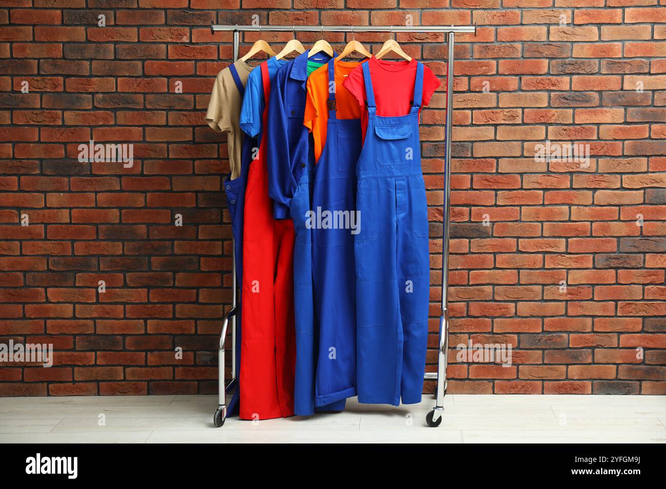 Different workers' uniforms on clothing rack near brick wall Stock ...