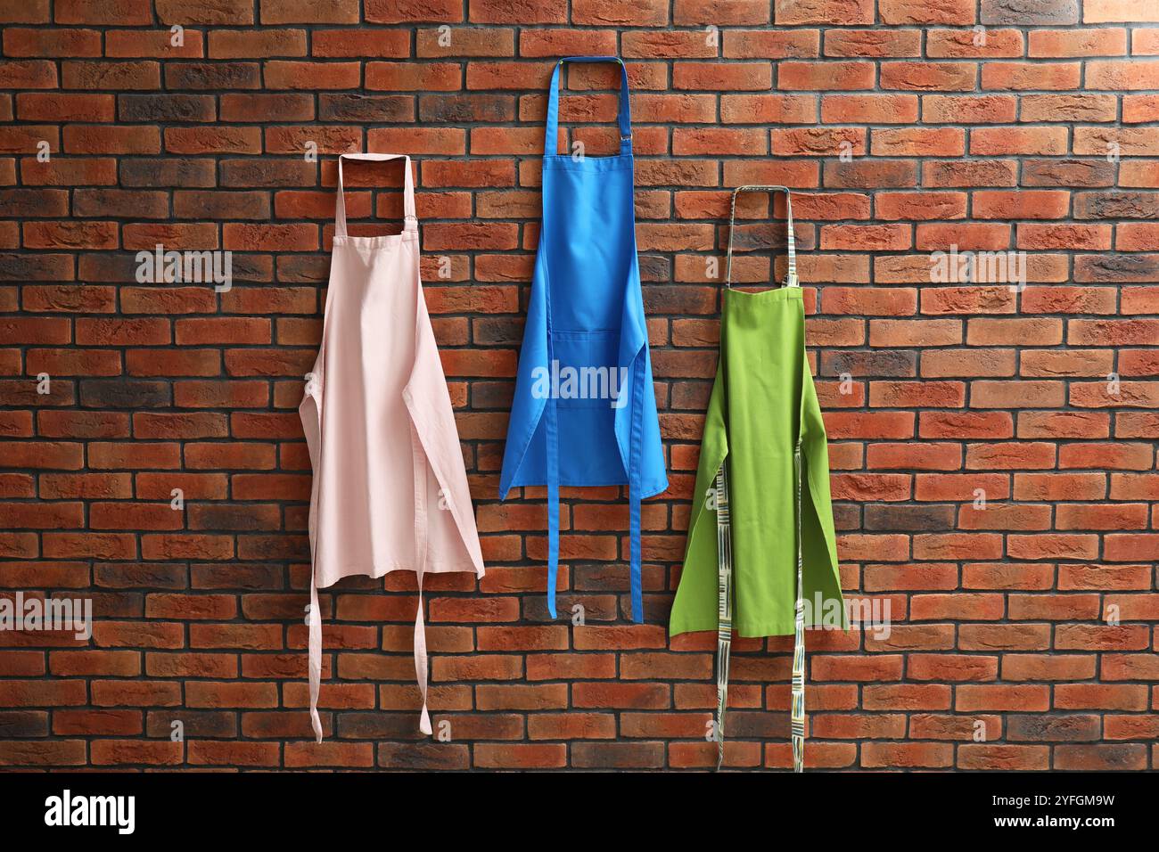 Many chef's aprons hanging on brick wall Stock Photo - Alamy