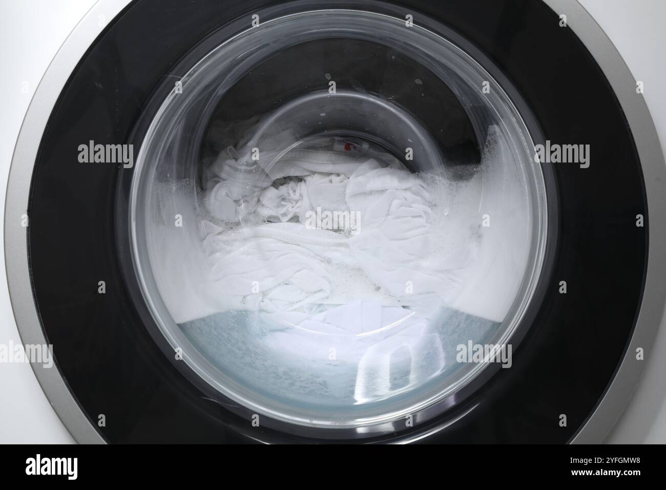 Washing machine with clothes and suds as background, closeup Stock ...