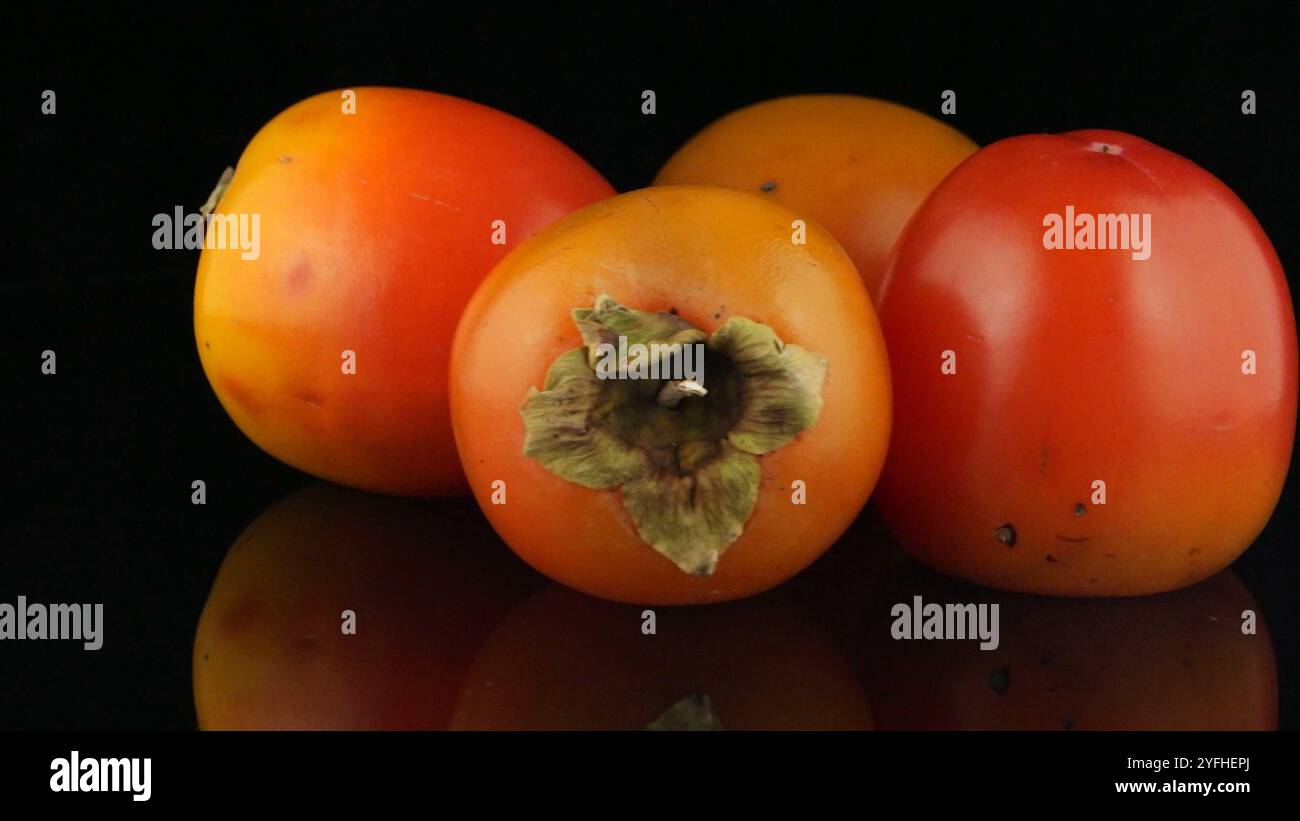 Red ripe persimmons rotating over black background Stock Photo - Alamy
