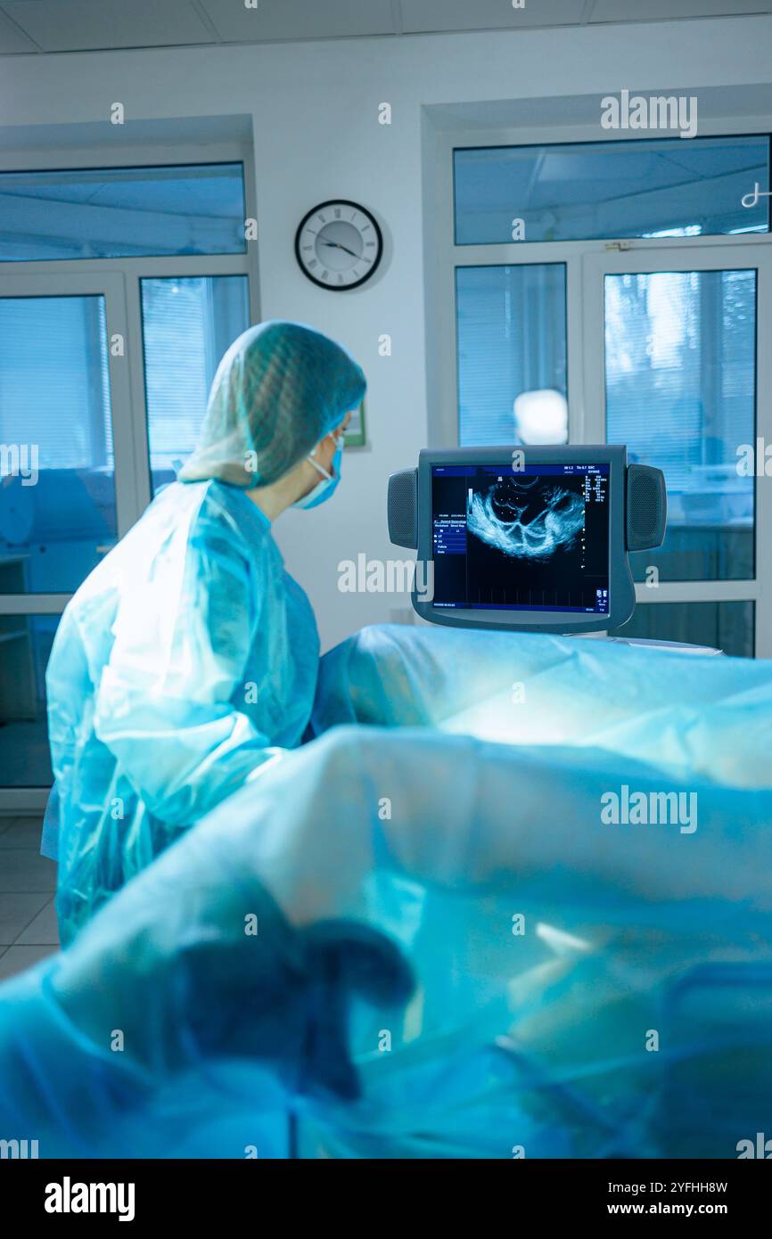 A female doctor performs an operation in a sterile operating room ...