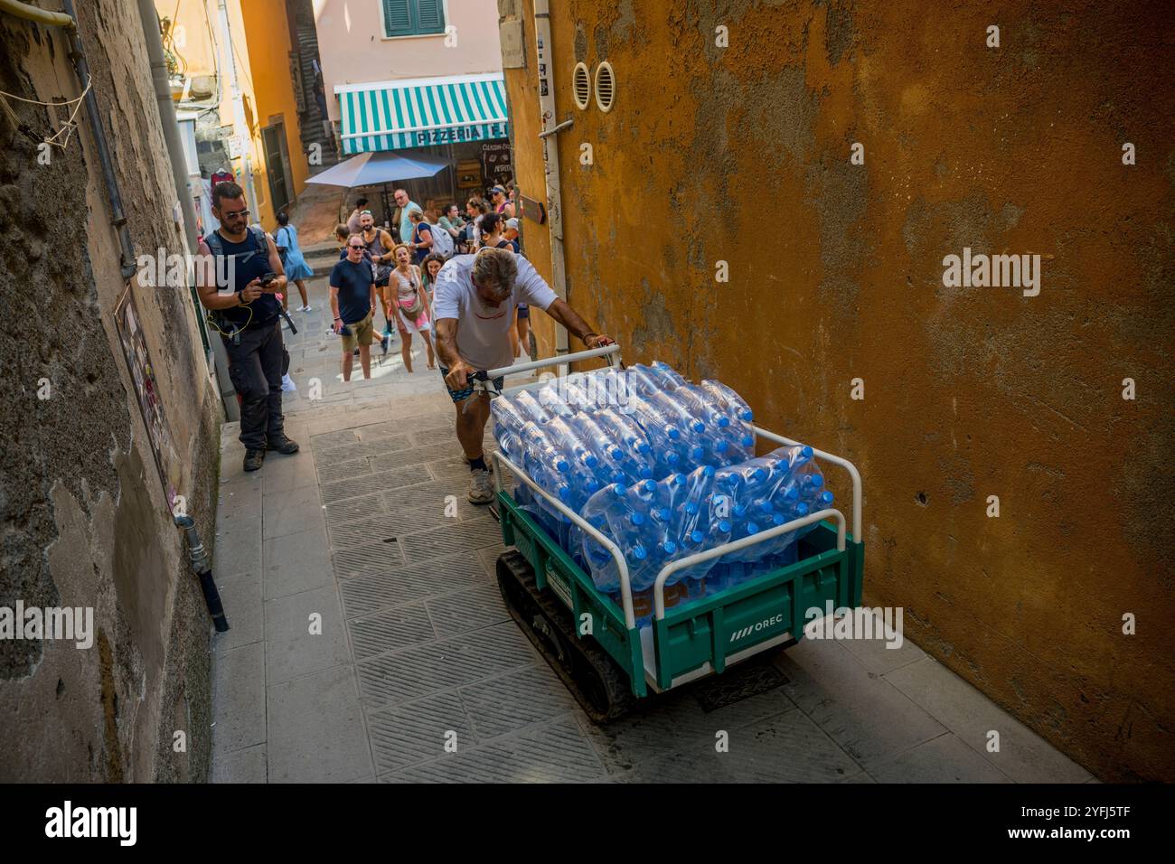Street scene with a man pushing a cart with water bottles through an ...