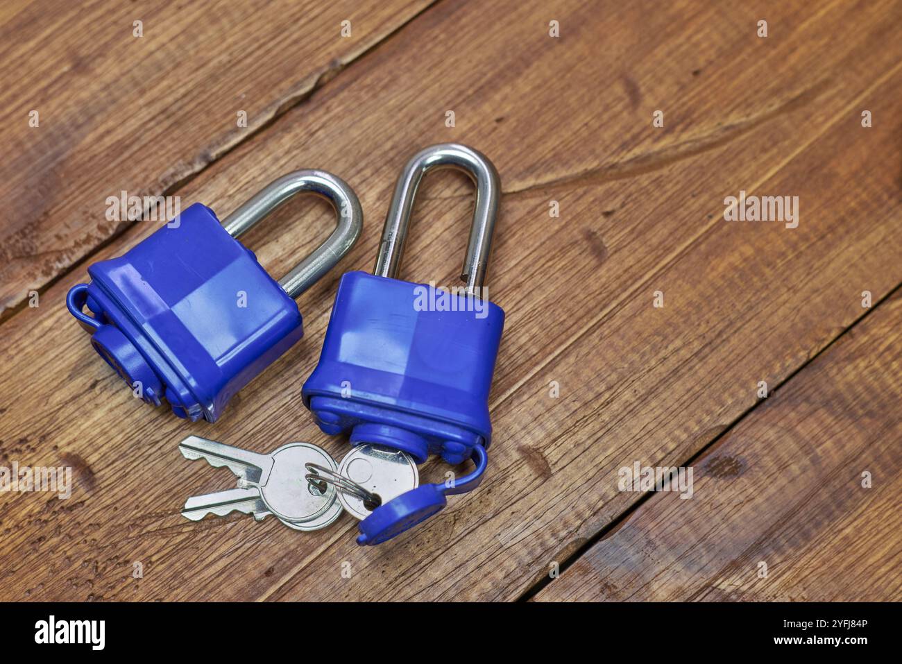 Blue plastic insulated padlock with key, on old wooden background, with ...