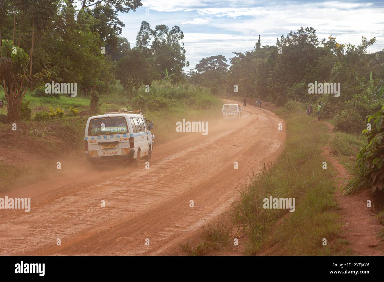 A taxi van, also known as "matatu" travels on a reddish dirt road in a ...