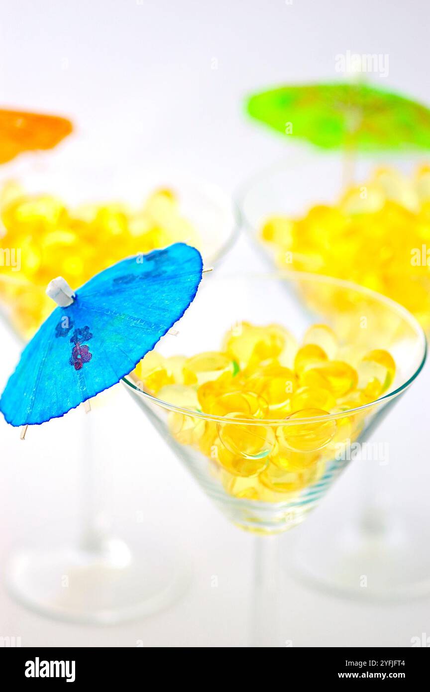 Three martini glasses filled with cod liver oil capsules, sources of ...
