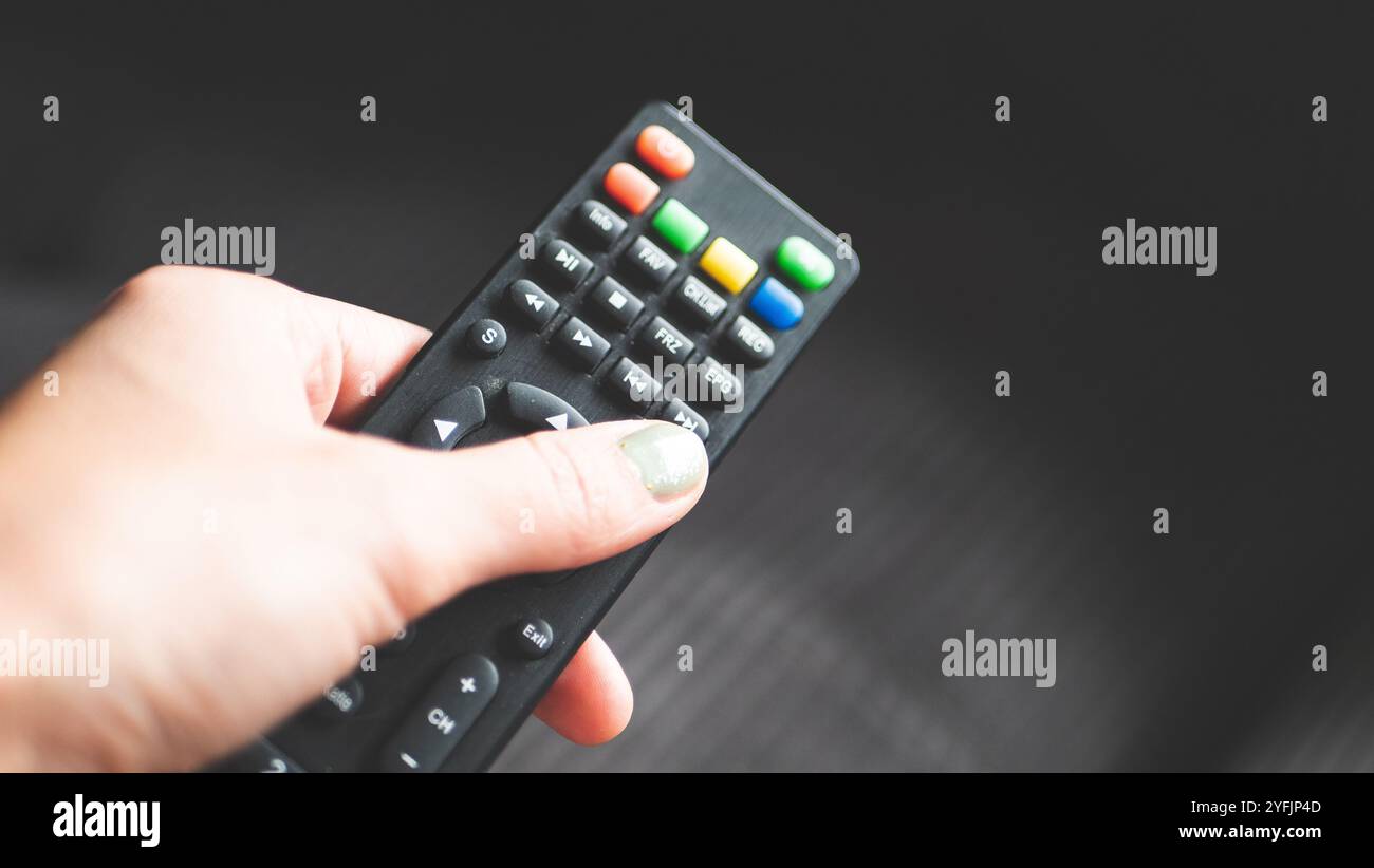 A hand holding remote control fingers black buttons tv Stock Photo - Alamy
