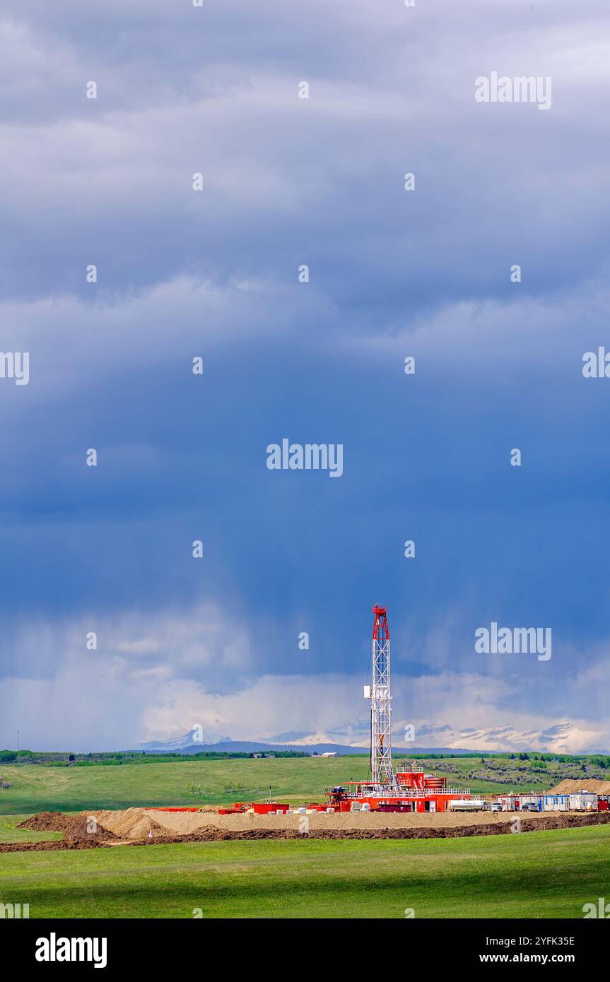A drilling rig in the Alberta foothills with stormy weather approaching ...
