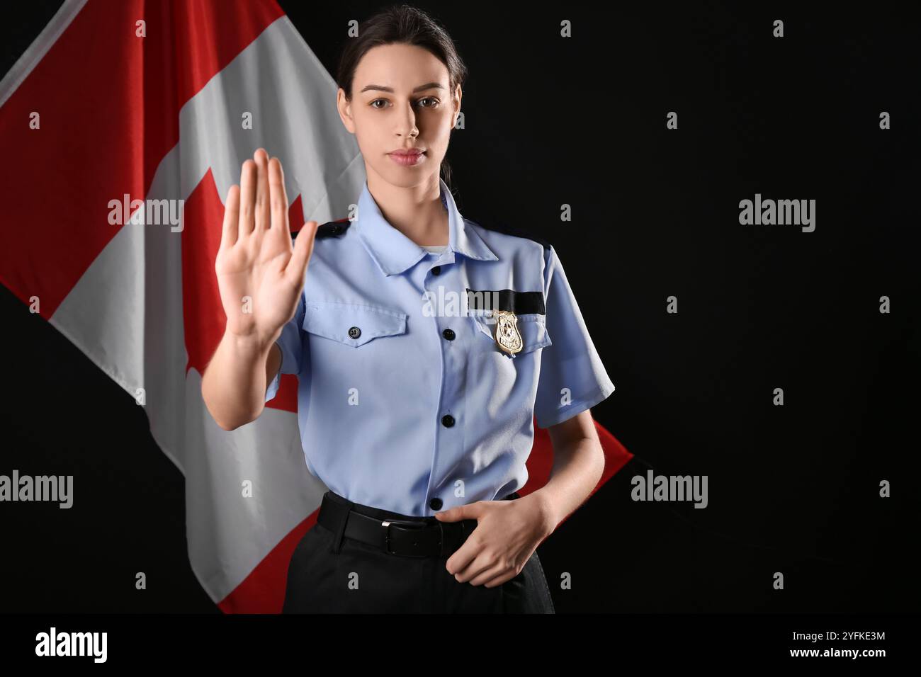 Female police officer showing STOP gesture and flag of Canada on dark ...