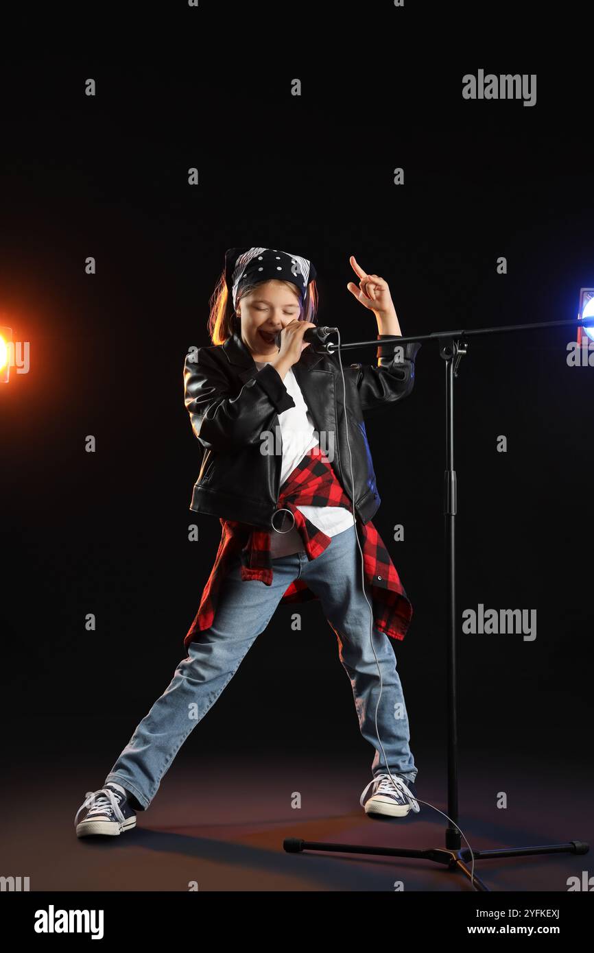 Cute little girl with microphone singing on stage Stock Photo - Alamy