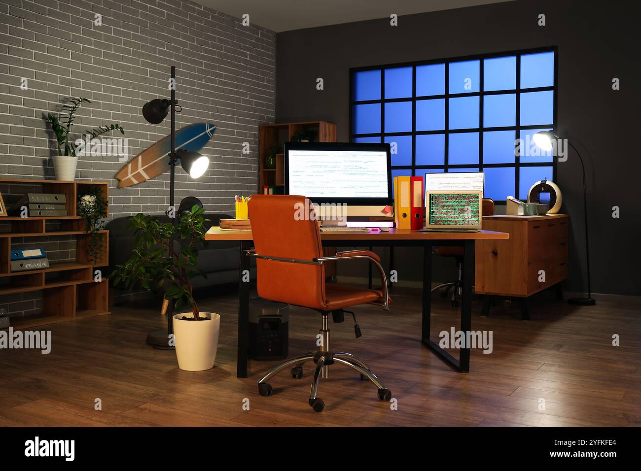 Interior of dark programmer's office with workplace and glowing lamps ...