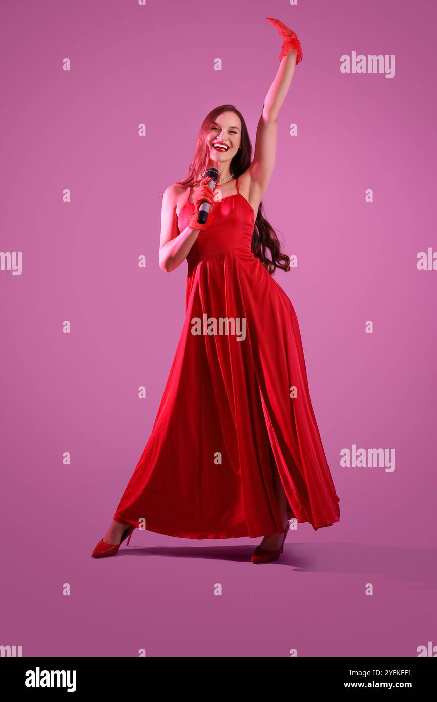Female singer with microphone dancing on pink background Stock Photo ...