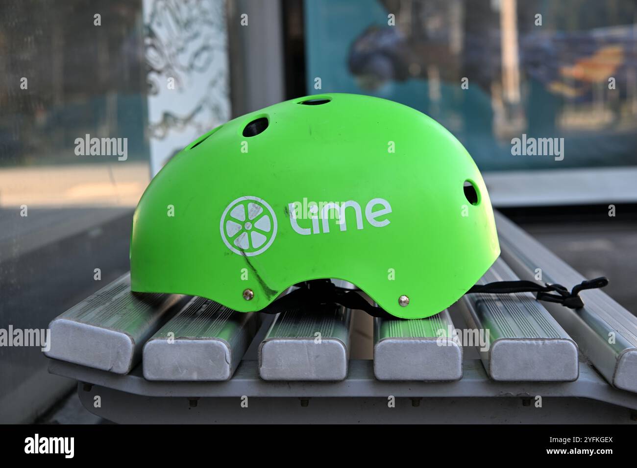 Side view of a Lime bike helmet left on the metallic bench seat of a ...