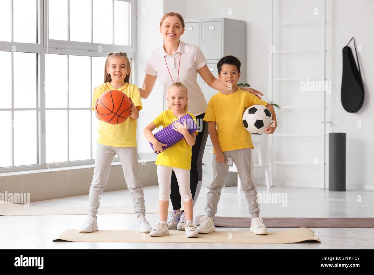 Cute little children with sports equipment and trainer in gym Stock ...