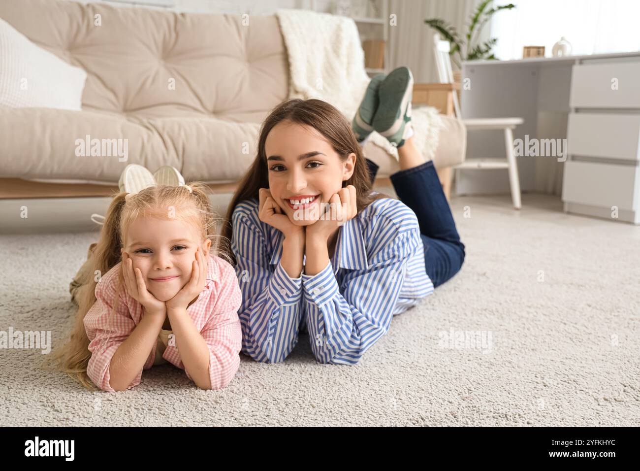 Nanny with cute little girl lying on carpet at home Stock Photo - Alamy