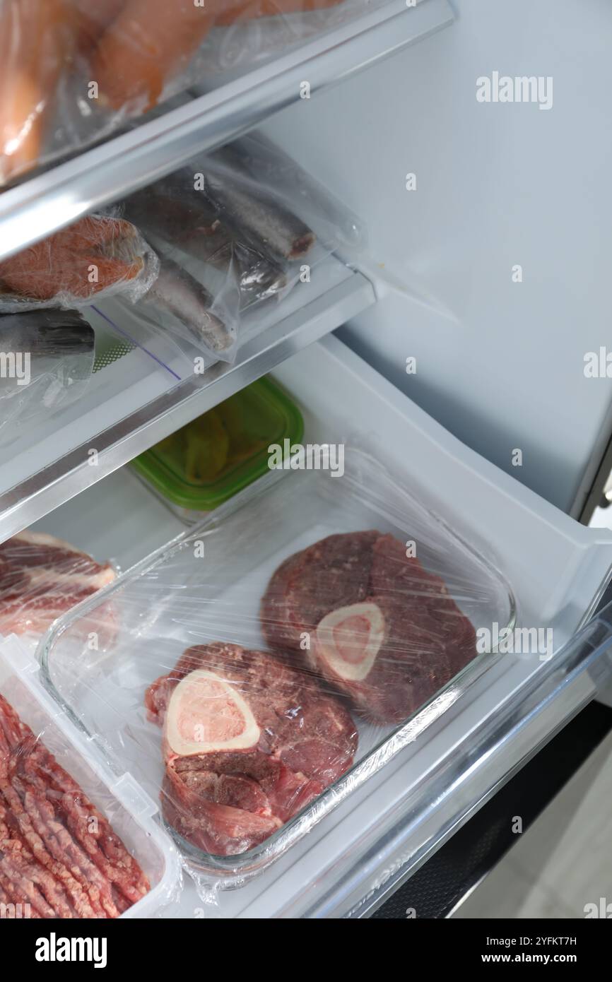 Frozen beef steaks in container of refrigerator, closeup Stock Photo ...