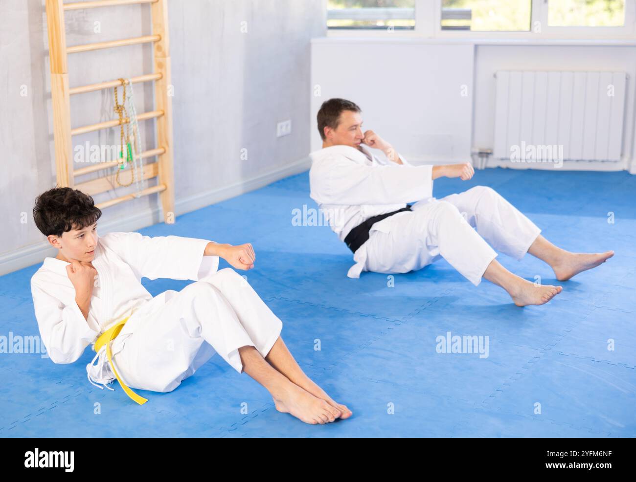 Teenage boy and trainer in kimono train abdominal muscles and do ...