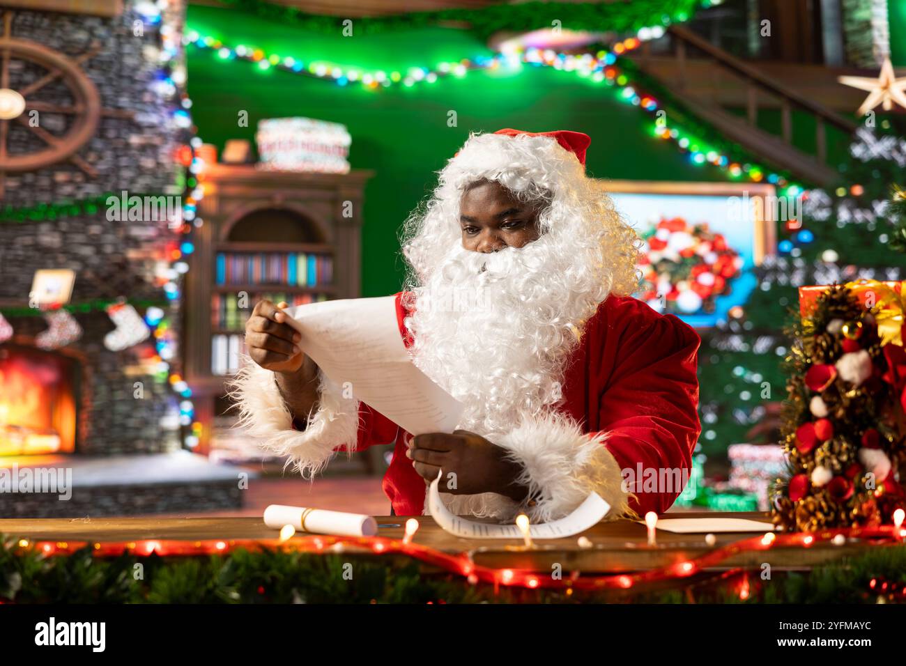 Santa Claus checking a letter while sitting in his rustic festive cabin ...