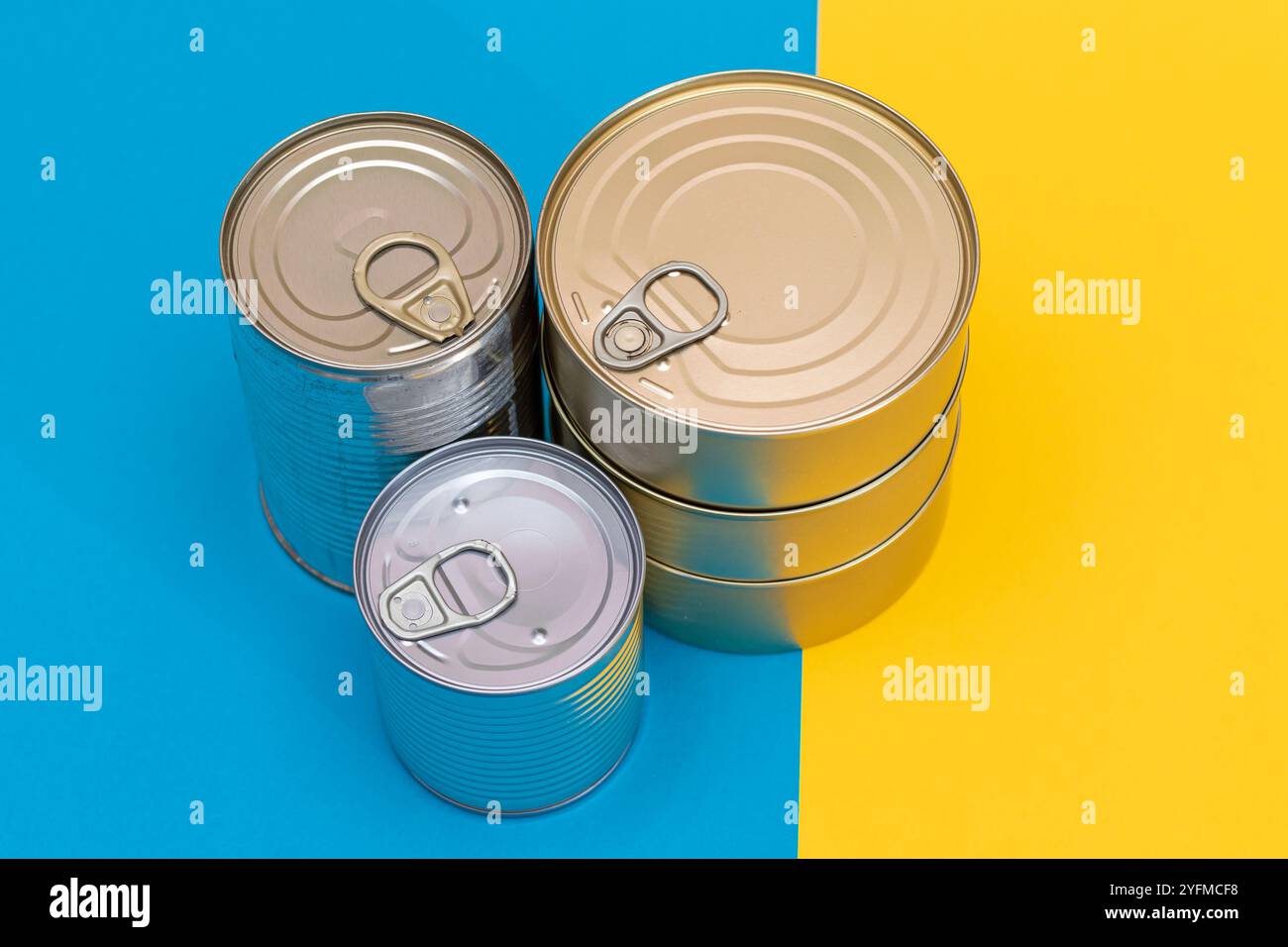 A Group of Stacked Tin Cans on Split Blue and Yellow Background. Canned ...