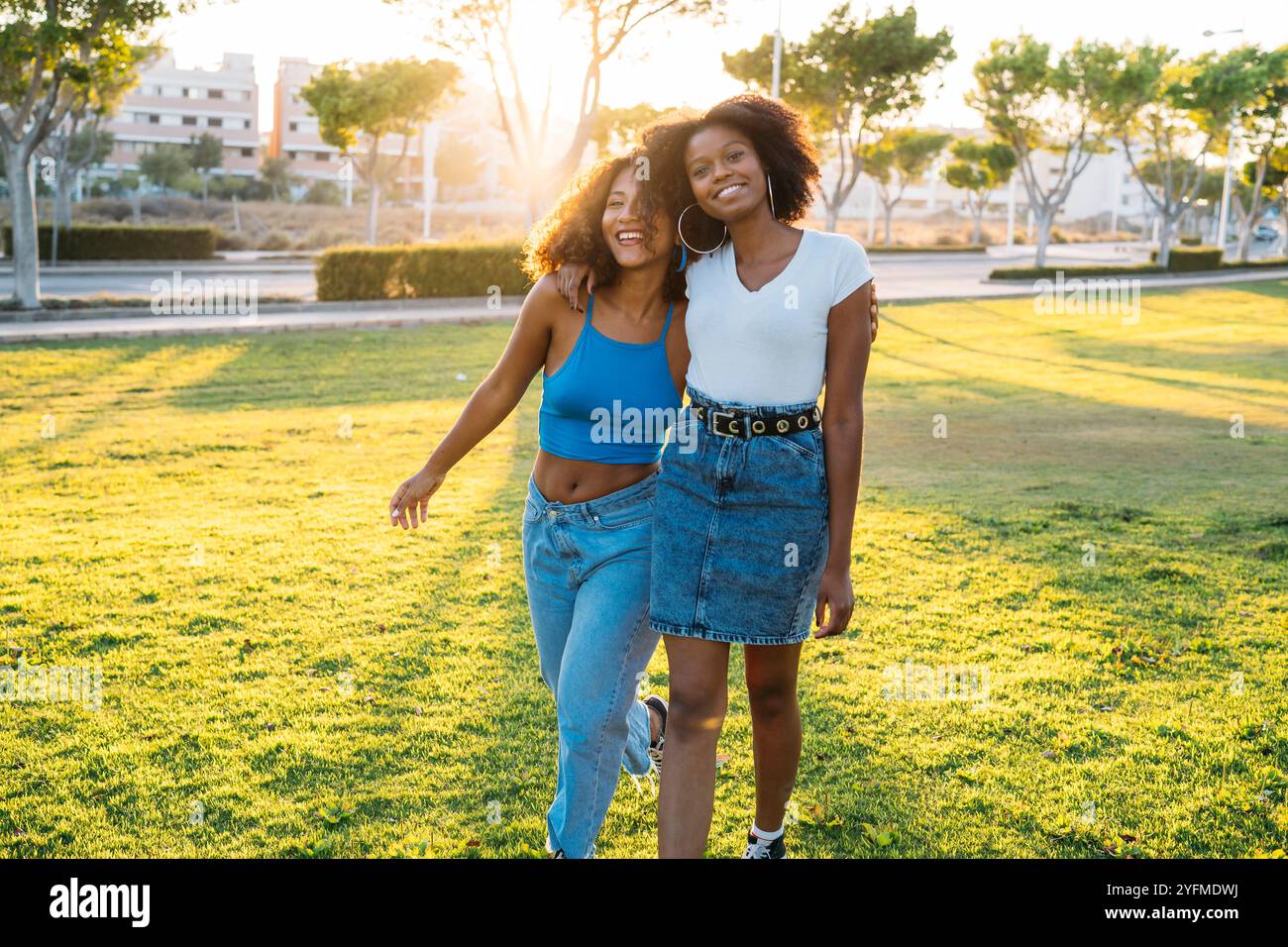 Two young women walking and laughing together in a park Stock Photo - Alamy