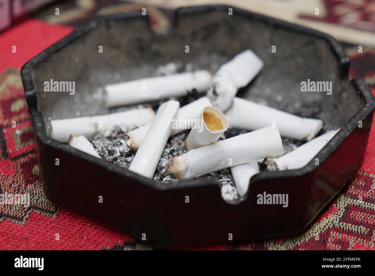 An ashtray filled with scattered cigarette butts and ashes from regular ...