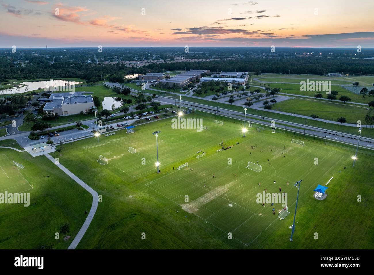 Public sports stadium with young people playing football game at sunset ...
