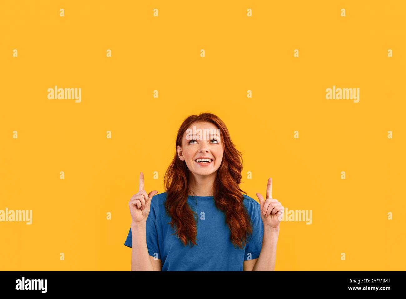 Cheerful Red-Haired Girl Pointing Fingers Up At Copyspace, Studio Shot ...