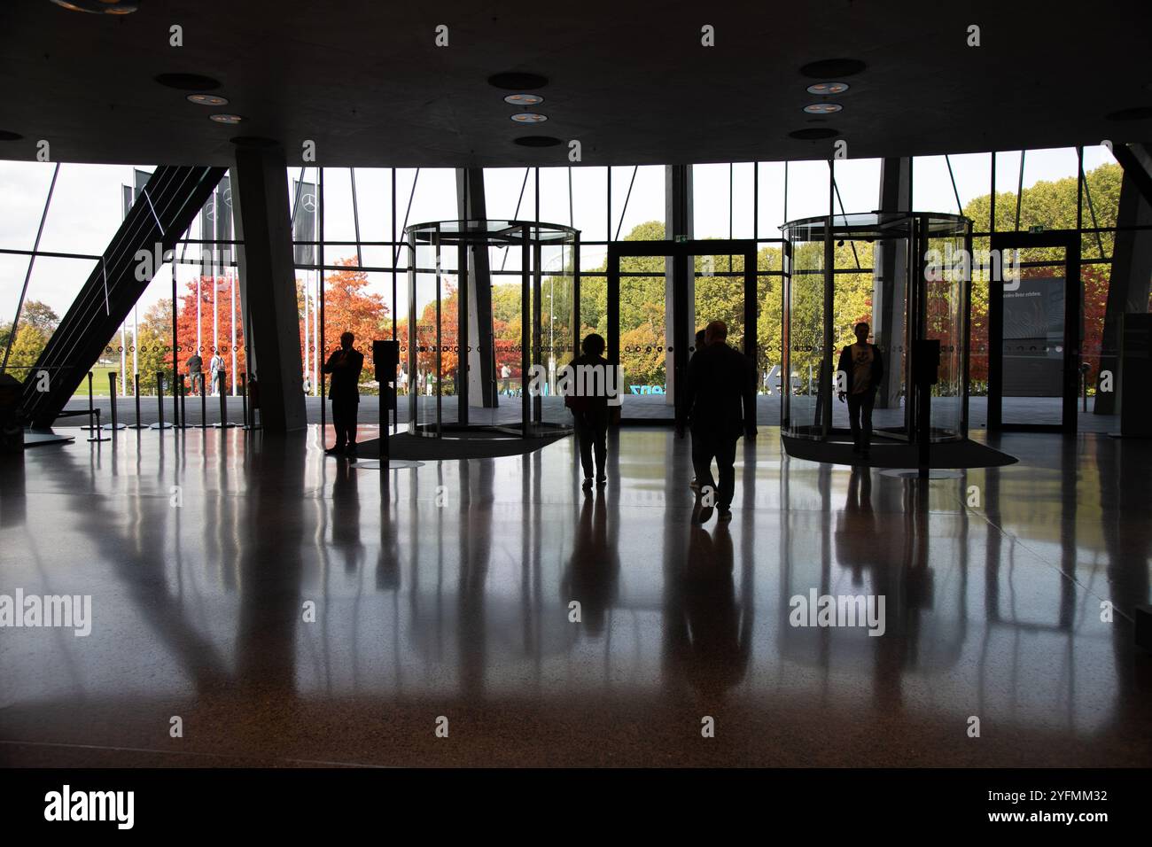 Silhouettes of people walking out of office building towards revolving ...