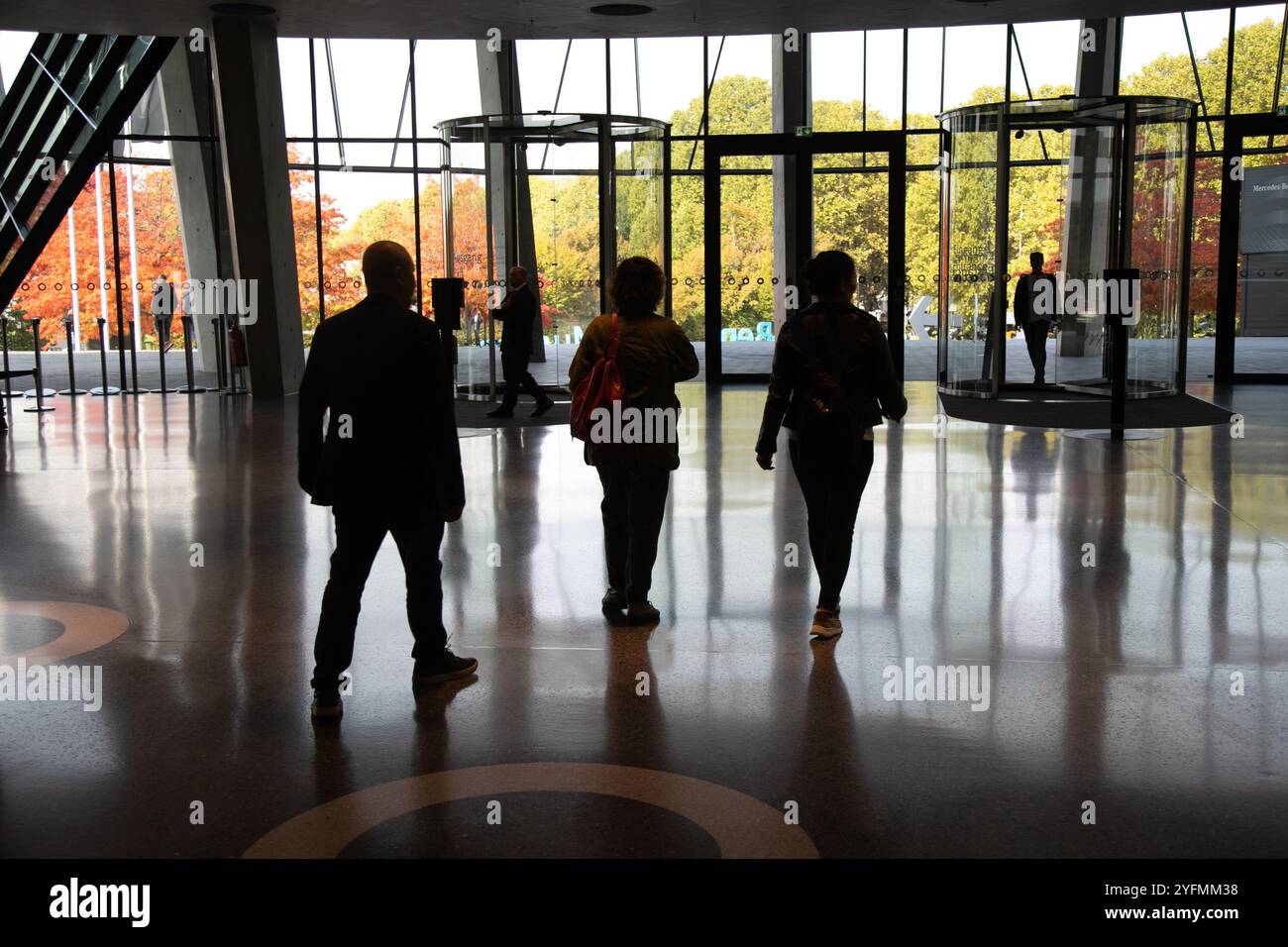 Silhouettes of people walking out of office building towards revolving ...