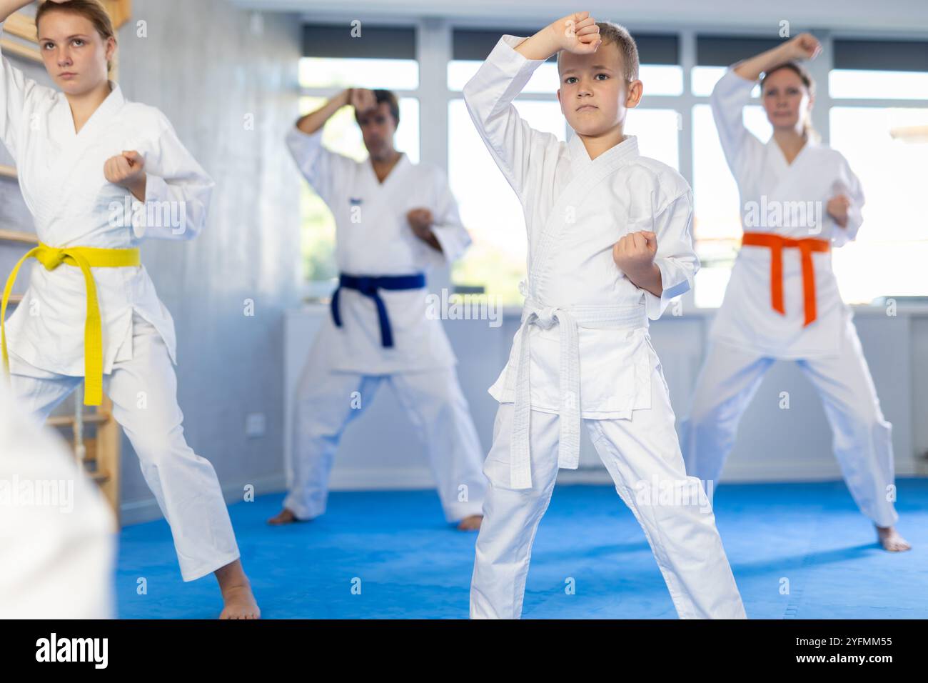 Boy in kimono with his family at group training in gym practice karate ...