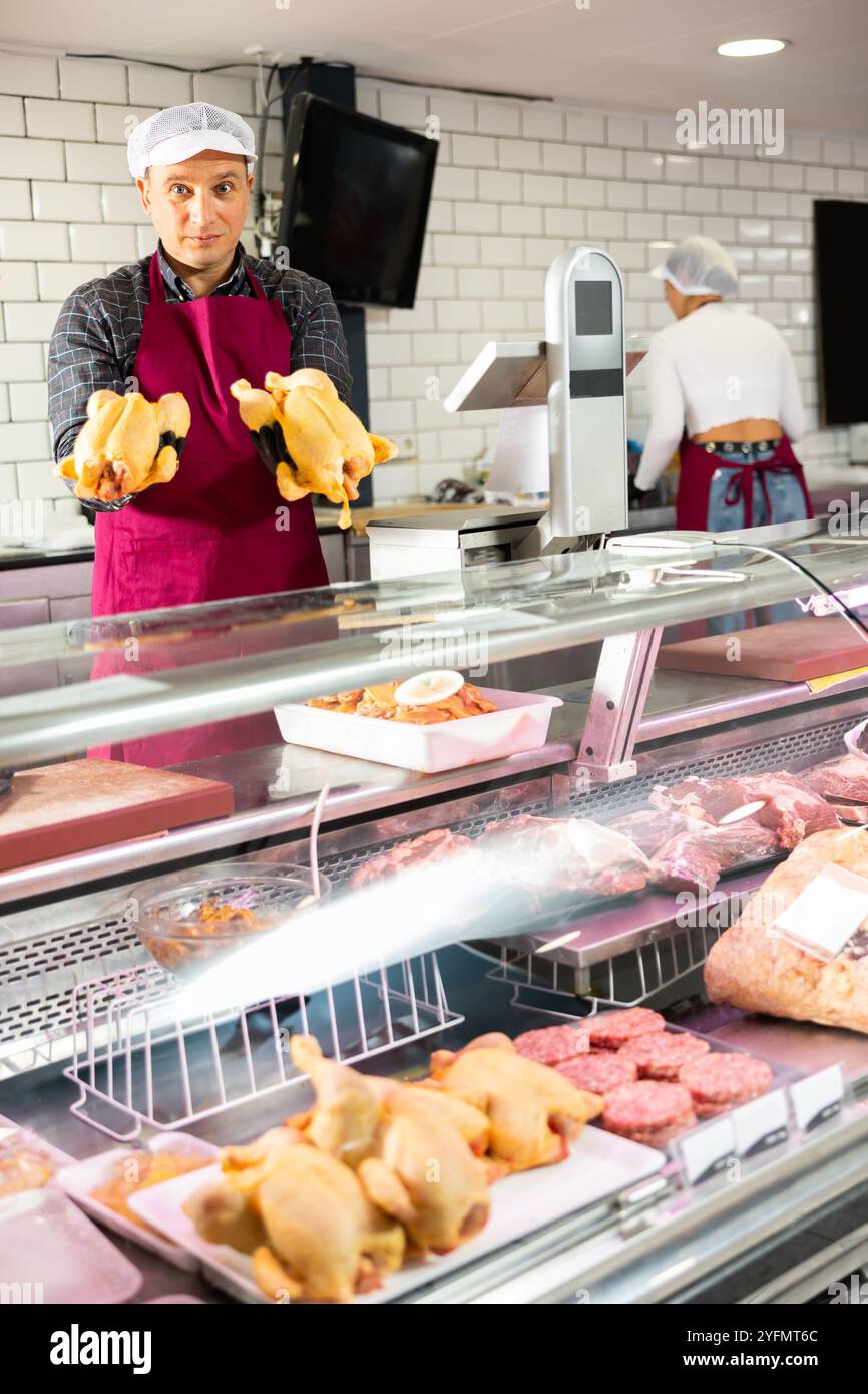 Adult butcher showing fresh gutted chickens in butchery Stock Photo - Alamy