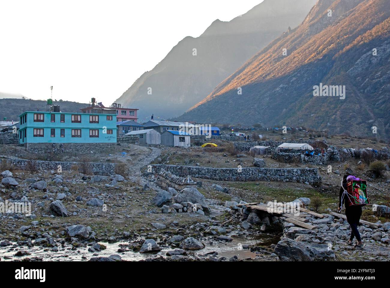 Porter heading into the new Langtang Vllage at dawn Stock Photo - Alamy