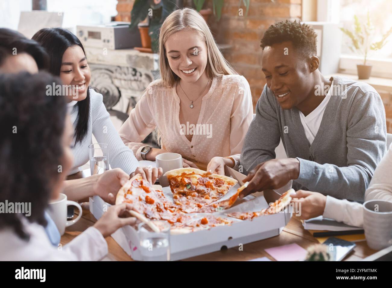 Happy multiracial colleagues eating pizza in office Stock Photo - Alamy
