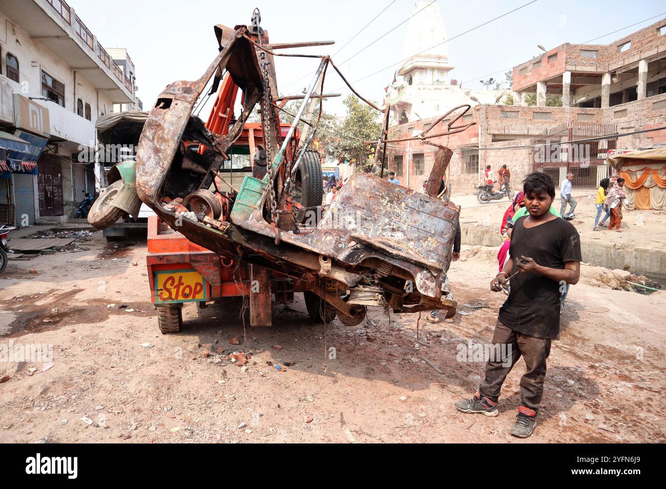 People remove the charred auto rickshaw after it was set on fire by a ...