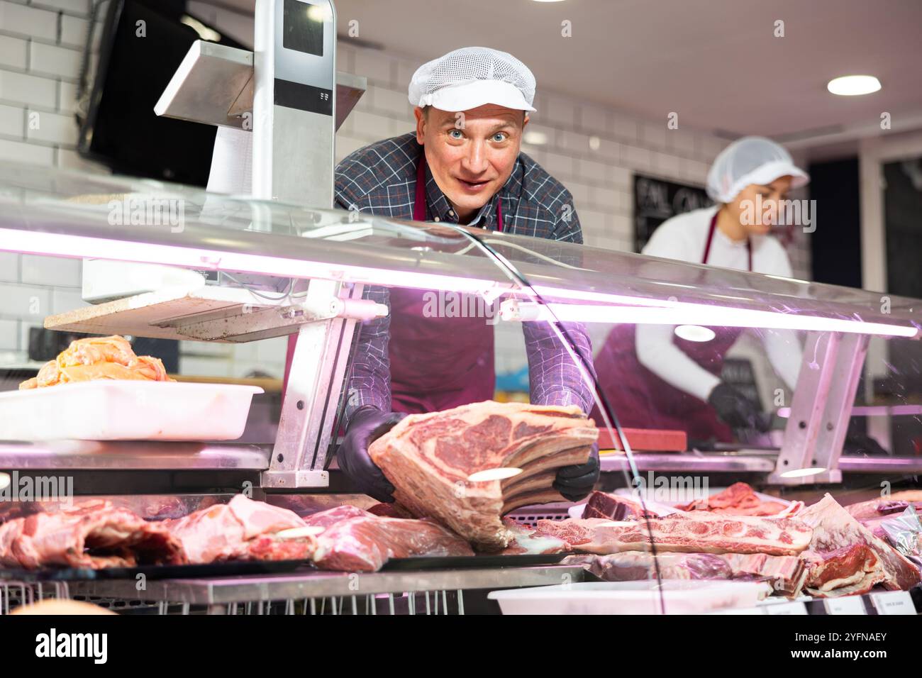 Adult man puts beef ribs in showcase Stock Photo - Alamy