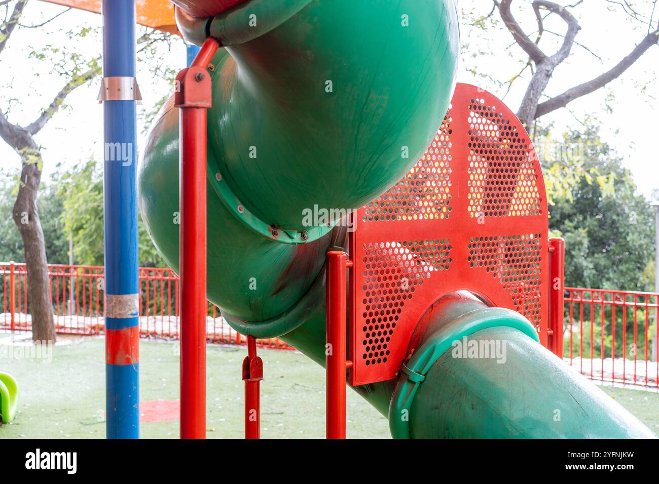 A vibrant green playground slide twists down from a structure in a park ...
