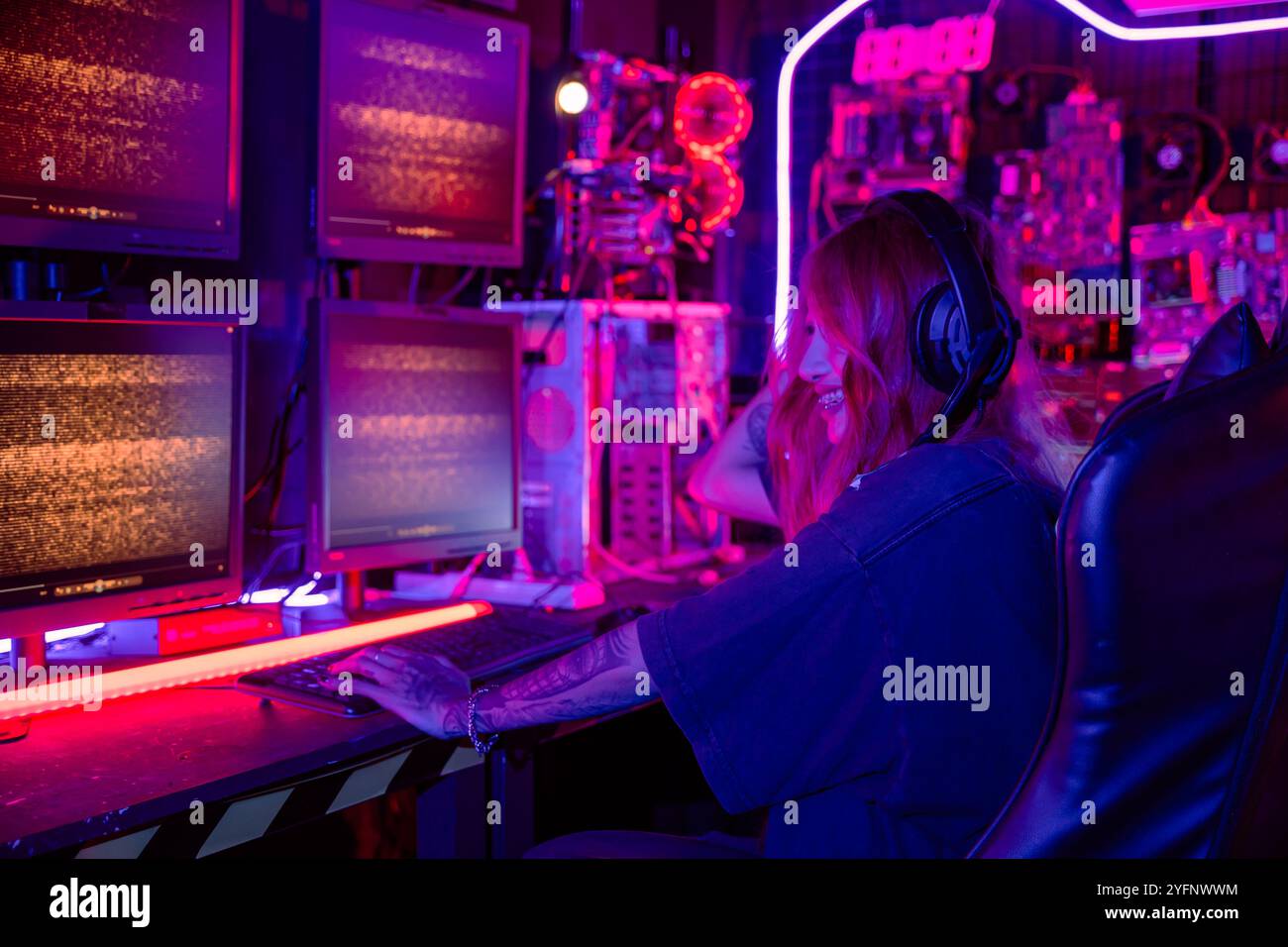 Woman hacker sitting in front of a computer typing on keyboard hacking ...